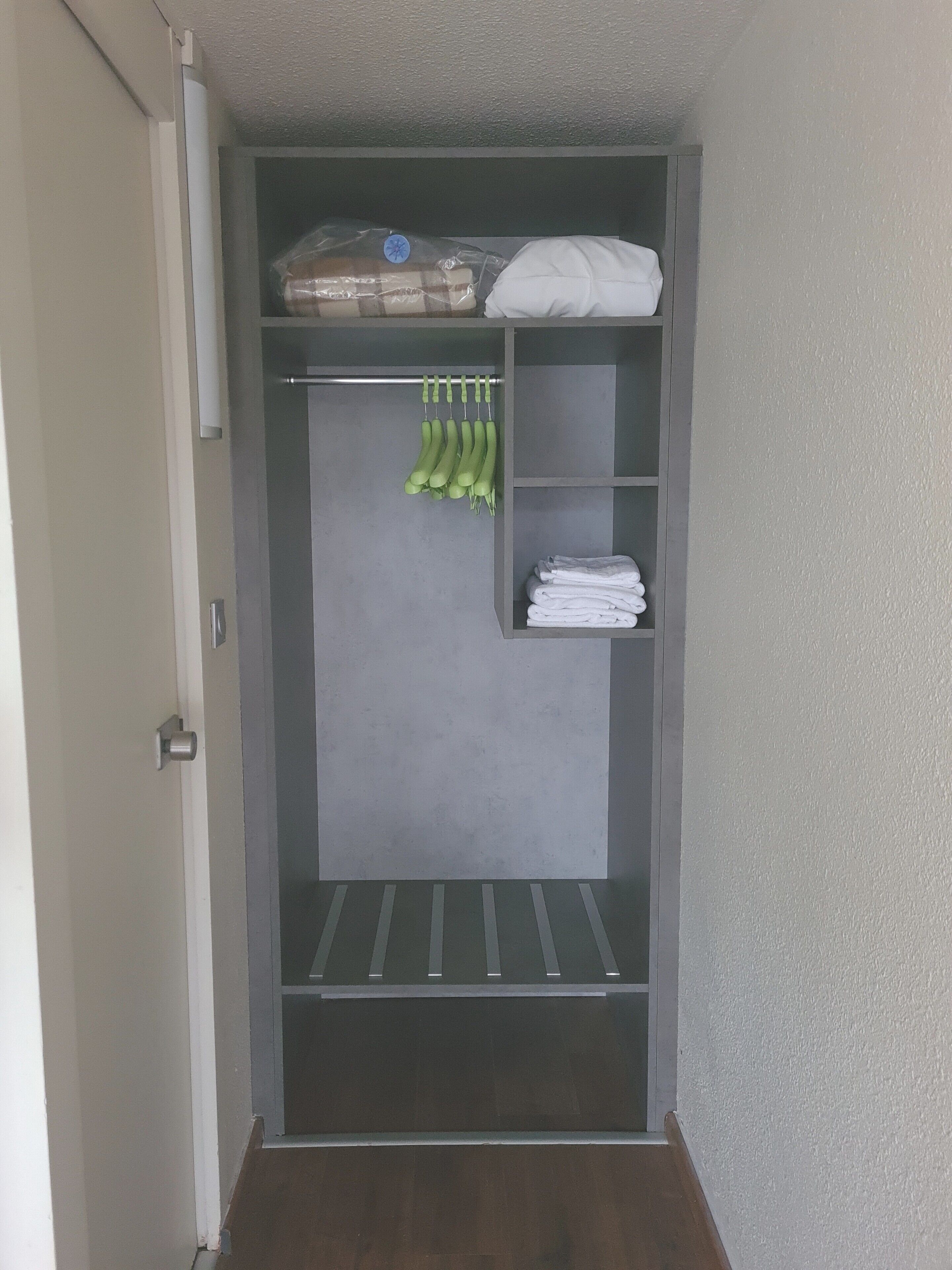Um closet amplo com barra para pendurar roupas, prateleiras e um porta-toalhas com toalhas dobradas.