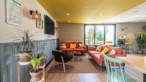 Uma sala de estar aconchegante com sofá, cadeiras, mesa de centro e plantas em vasos.