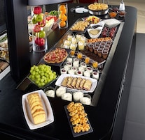 Uma mesa de buffet com diversos alimentos, incluindo frutas, doces e sobremesas.