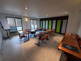 Uma sala de conferências com várias mesas, cadeiras e um quadro branco.