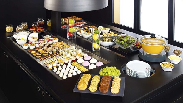Buffet com diversas opções de comida, incluindo doces, frutas e saladas.