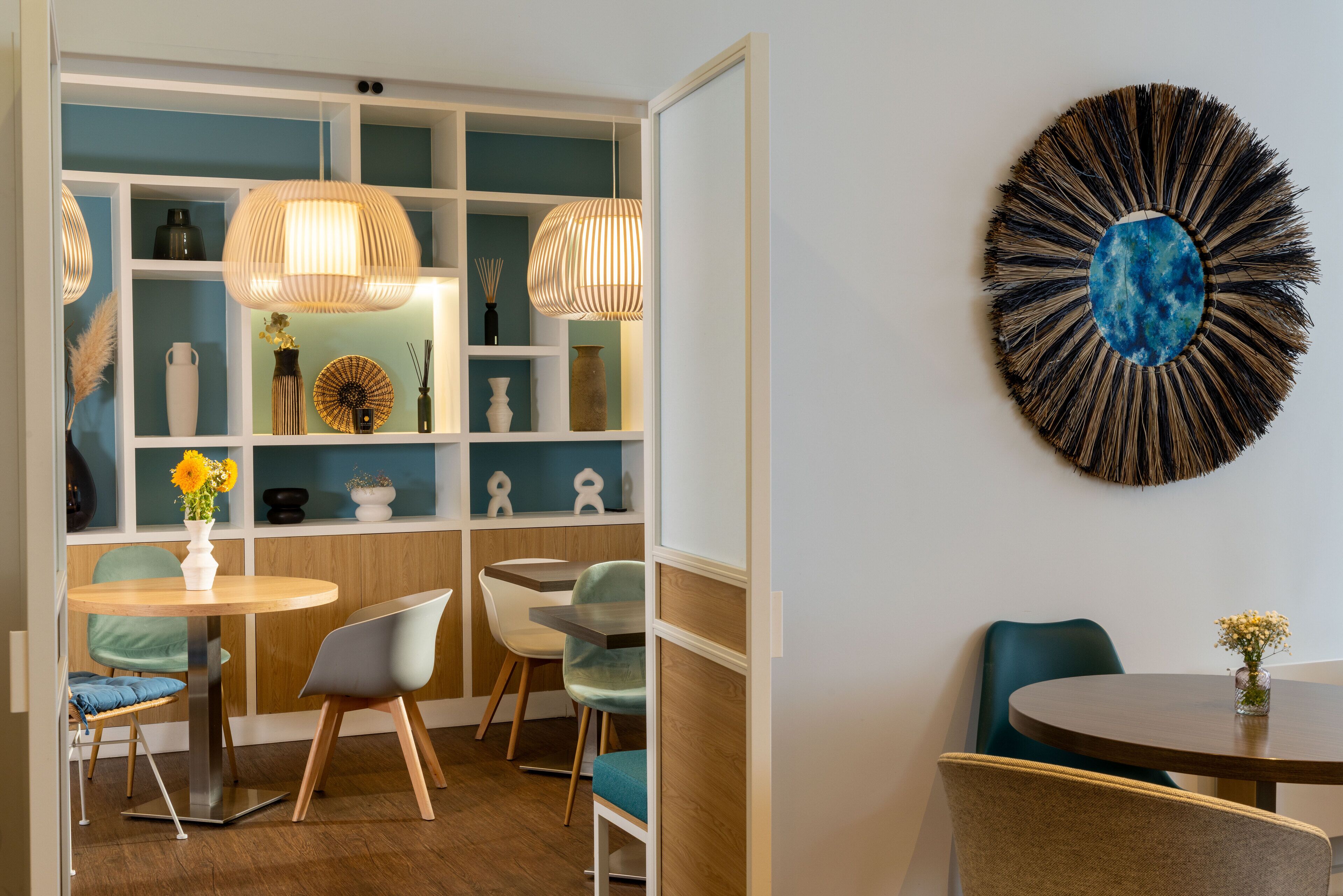 Uma sala de jantar com uma mesa redonda, cadeiras e um objeto decorativo na parede.
