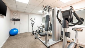 Uma academia com equipamentos de ginástica, um relógio e uma bola de exercícios azul.