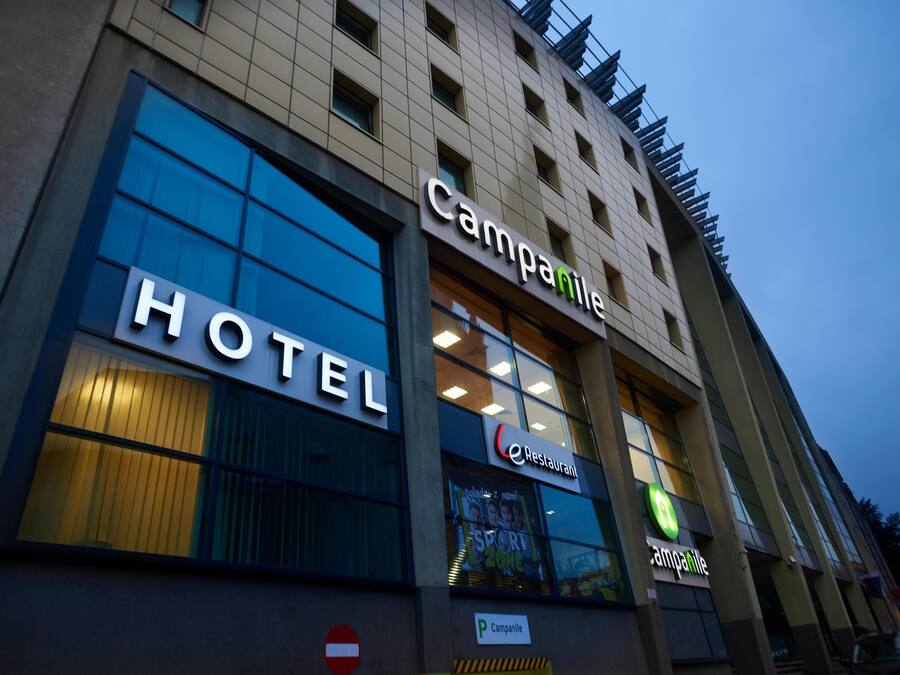 Um hotel com uma placa indicando 'Campanile' e outra placa com a palavra 'Restaurante'.