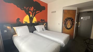 Quarto de hotel com duas camas, um mural de uma árvore e animais, e maçaneta em formato de leão.
