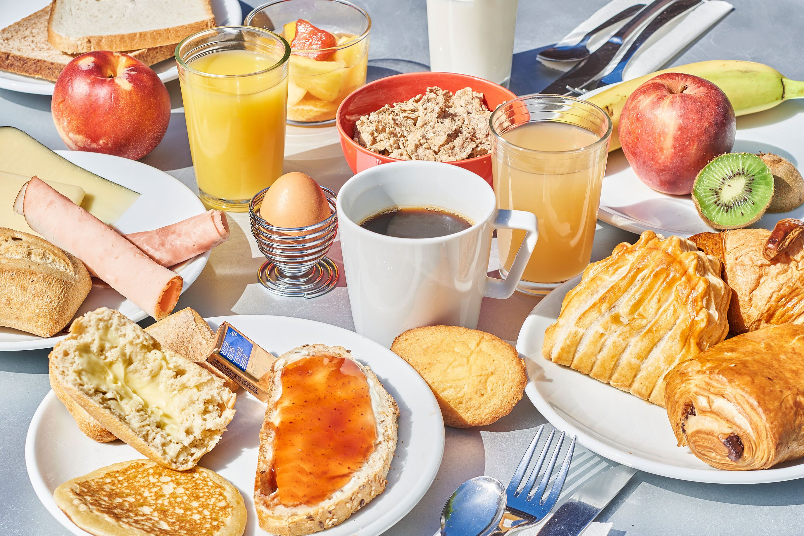 Mesa de café da manhã com diversos alimentos e bebidas.