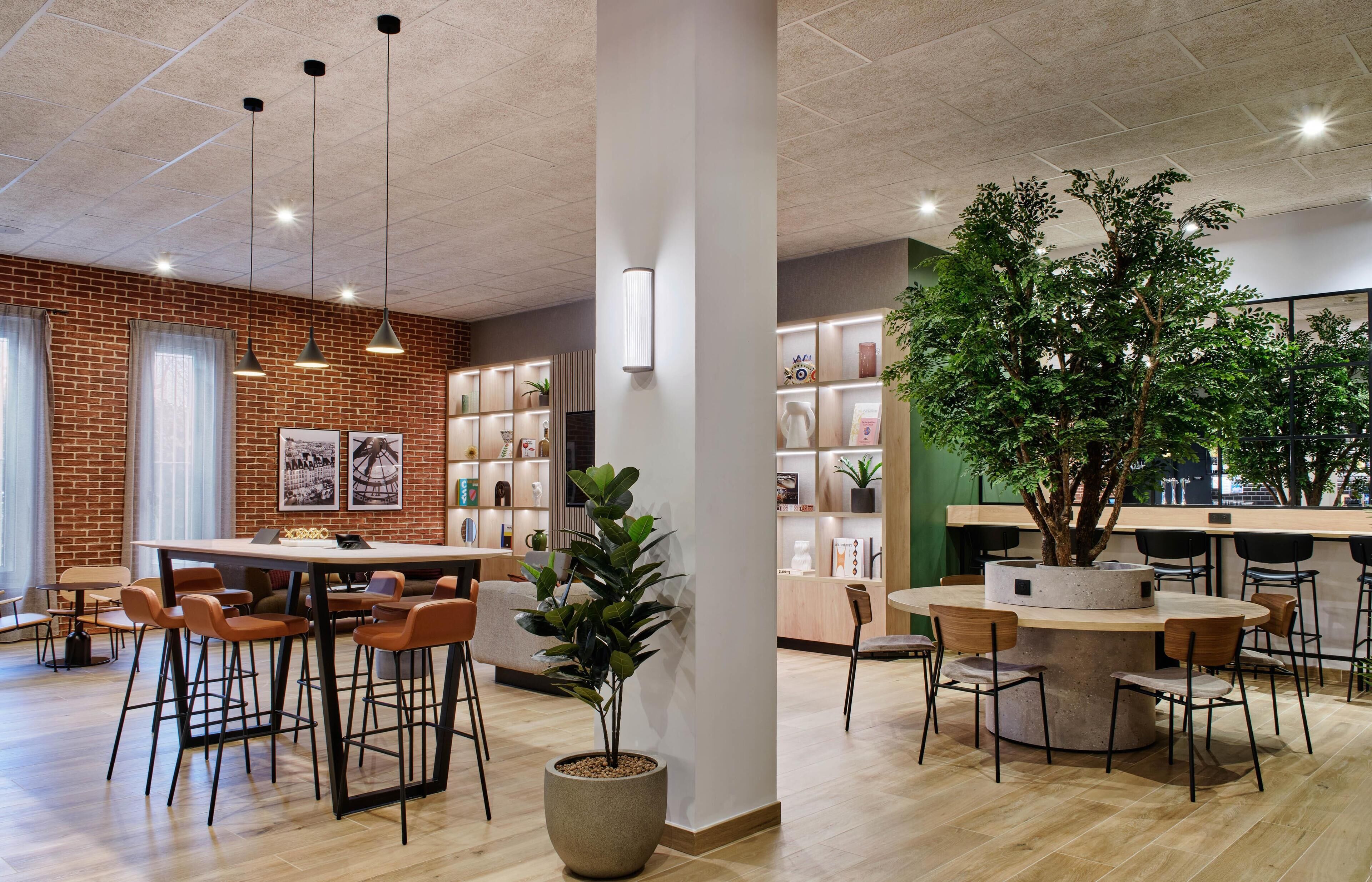 Decoração moderna com parede de tijolos, uma grande árvore dentro de casa e um espaço de bar.