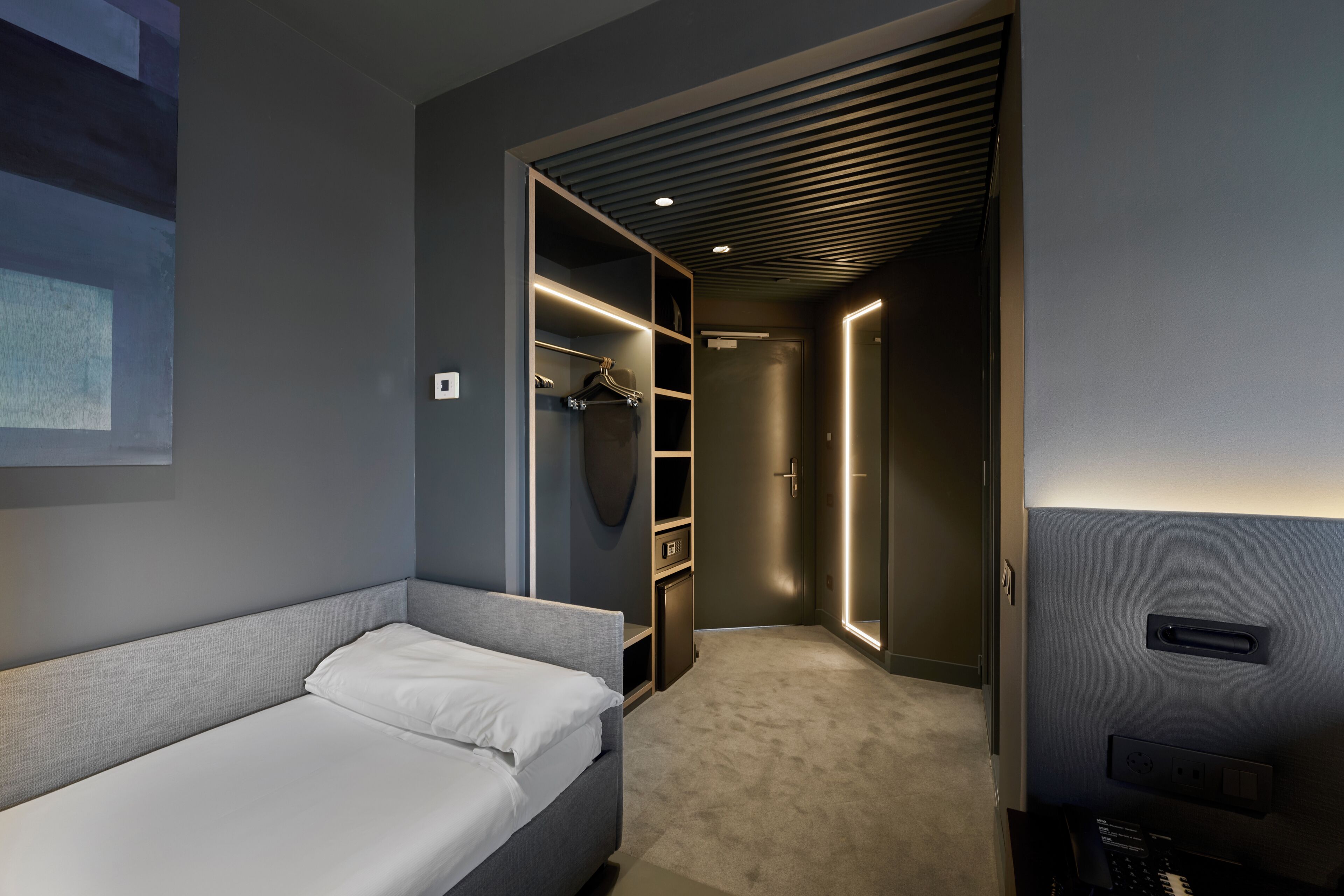 Quarto moderno com uma cama de solteiro, closet espaçoso e escrivaninha embutida.
