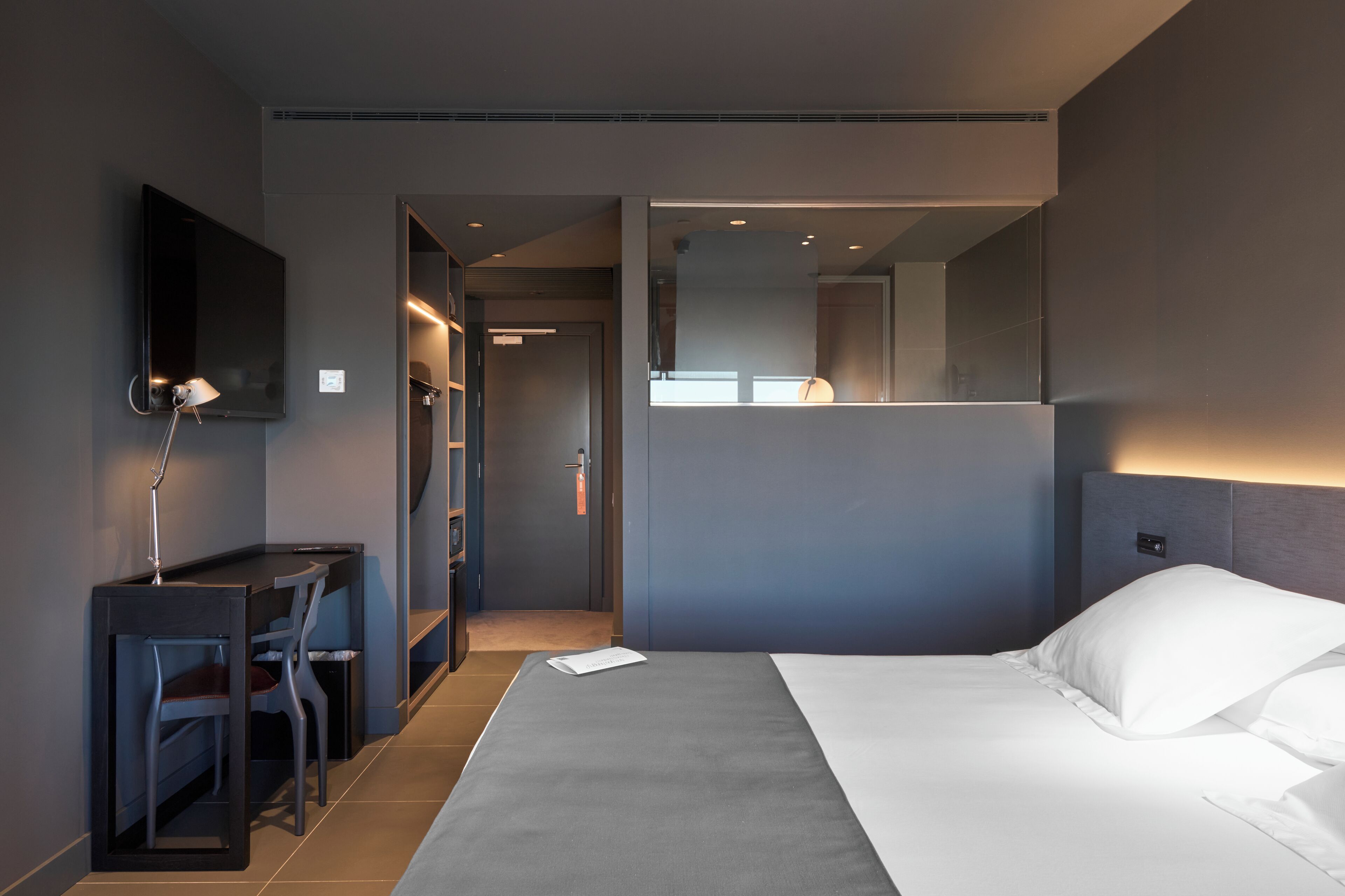 Quarto de hotel moderno com cama, escrivaninha e cadeira.