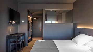 Quarto de hotel moderno com cama, escrivaninha e cadeira.