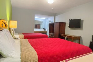 Quarto de hotel com duas camas, televisão, espelho, guarda-roupa e escrivaninha.
