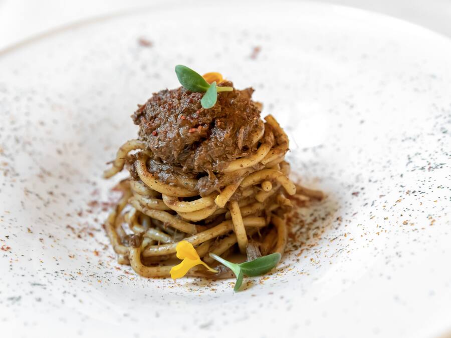 Um prato de espaguete com carne e acompanhamentos.