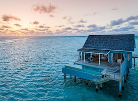 Uma bungalow sobre a água, com terraço, piscina e vista para o oceano.