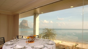 Mesa de jantar posta para seis com vista para o oceano e palmeiras.