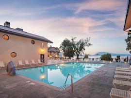 Piscina com espreguiçadeiras e um edifício com luminária.
