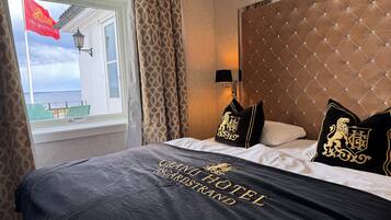 Quarto de hotel com uma cama grande, vista para o mar e uma bandeira.