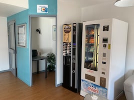 Quarto com máquina de vendas, micro-ondas e frigorífico.