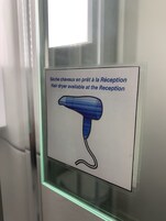 Sinal indicando que um secador de cabelo está disponível na recepção.