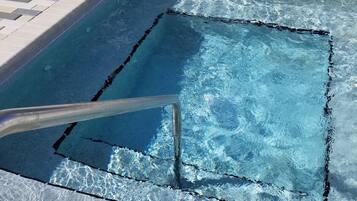 Piscina com linha de água cristalina, rodeada por um deck revestido de azulejos.