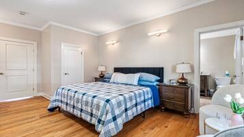 Quarto com cama, mesas de cabeceira, cômoda e uma cadeira.