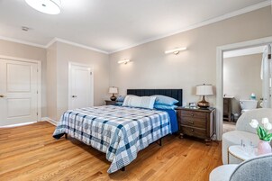 Quarto com cama, mesas de cabeceira, cômoda e uma cadeira.