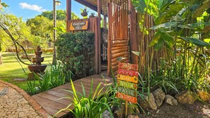 Uma pérgola de madeira com uma placa que diz 'Cantinho de Paz' e outra placa com palavras relacionadas a bem-estar.