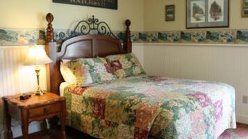 Quarto com cama de madeira, roupa de cama floral, mesa de cabeceira com abajur e um letreiro na parede com a inscrição "Boston & Maine Railroad".