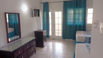 Quarto com cama, cómoda, televisão e janela com cortinas.