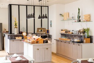 Cozinha moderna com ilha central, iluminação pendente e diversos eletrodomésticos e utensílios.