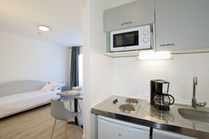 Uma kitchenette compacta com micro-ondas, cafeteira e pia.