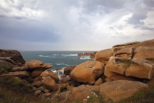 Litoral rochoso com grandes pedras e o oceano ao fundo.
