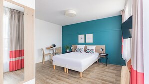 Quarto de hotel moderno com uma cama grande, uma mesa e uma cadeira.