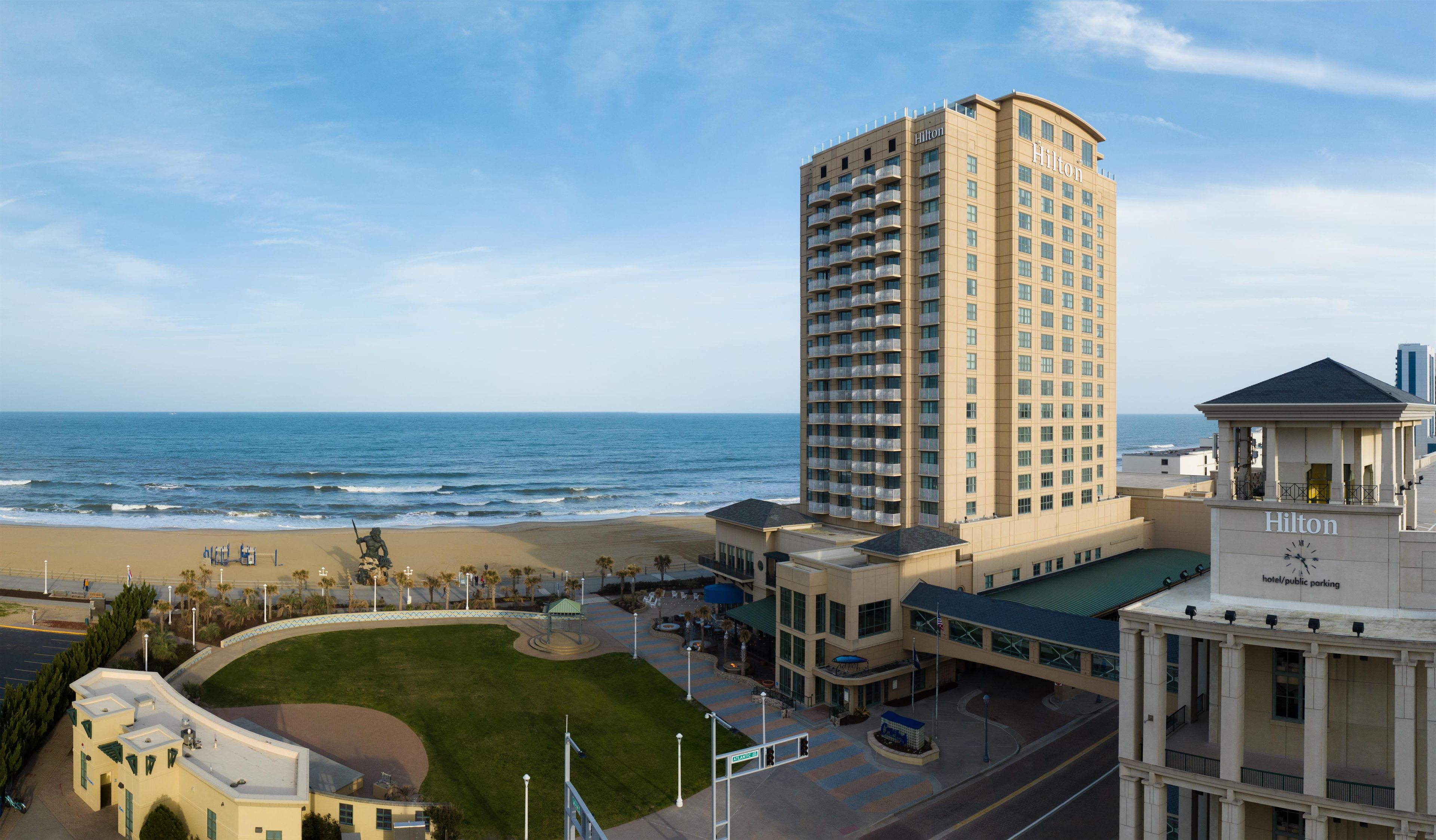 Hotel à beira-mar com vista para o oceano, área de estacionamento e um edifício com relógio.
