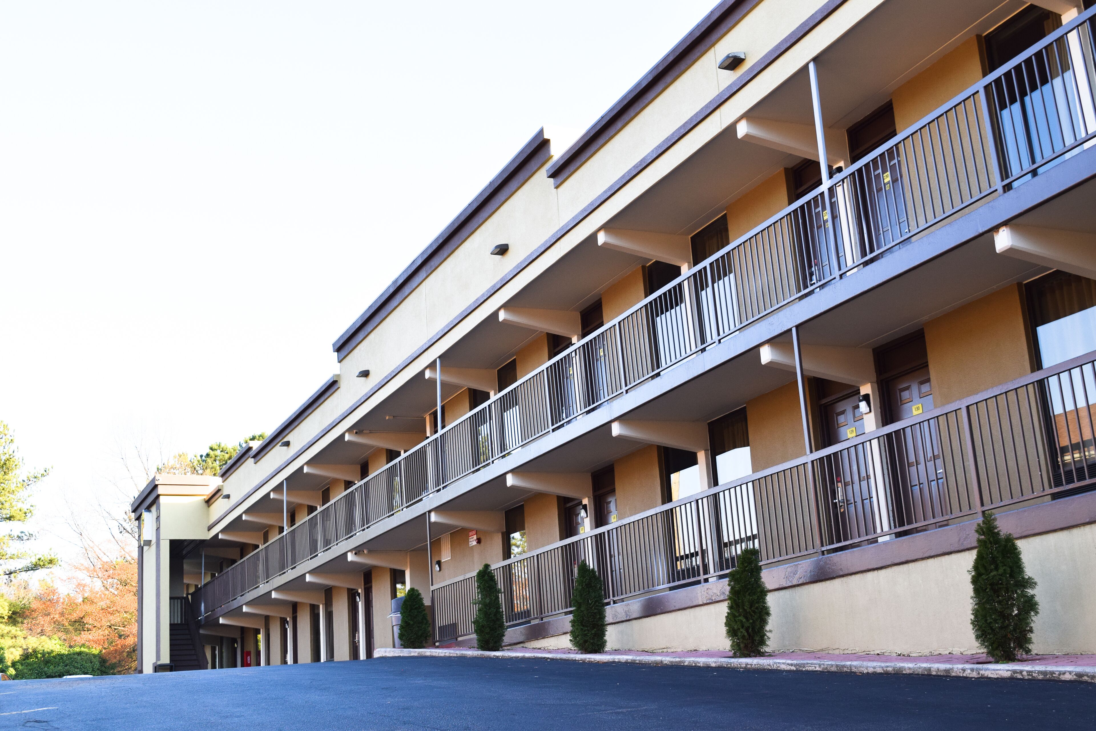 Um hotel de vários andares com varandas, estacionamento e céu claro.