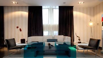 Uma sala de estar moderna com uma mesa de centro de vidro, um sofá branco e duas cadeiras pretas.
