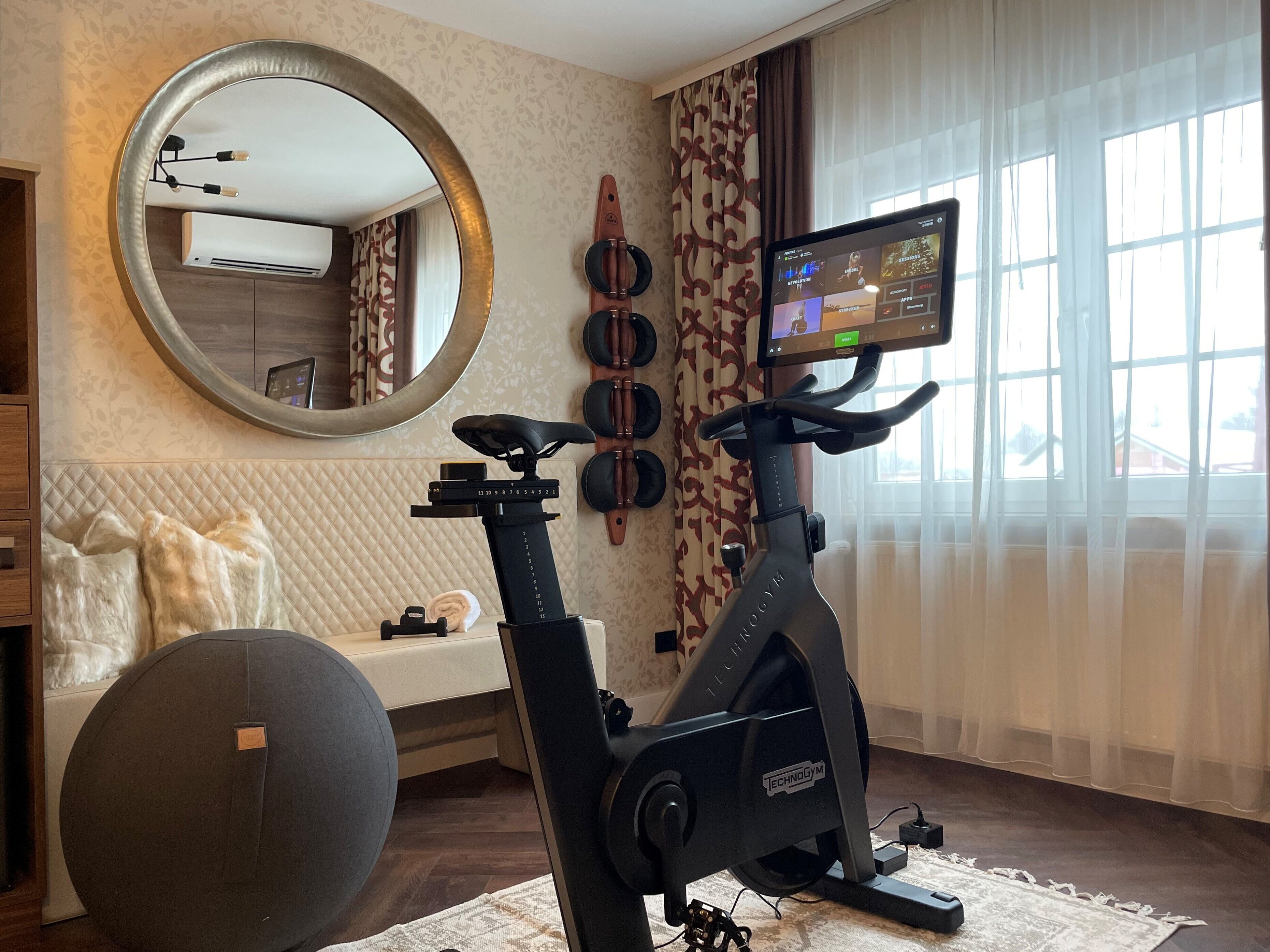 Uma academia em casa com uma bicicleta de exercícios, um espelho grande e uma bola de yoga.