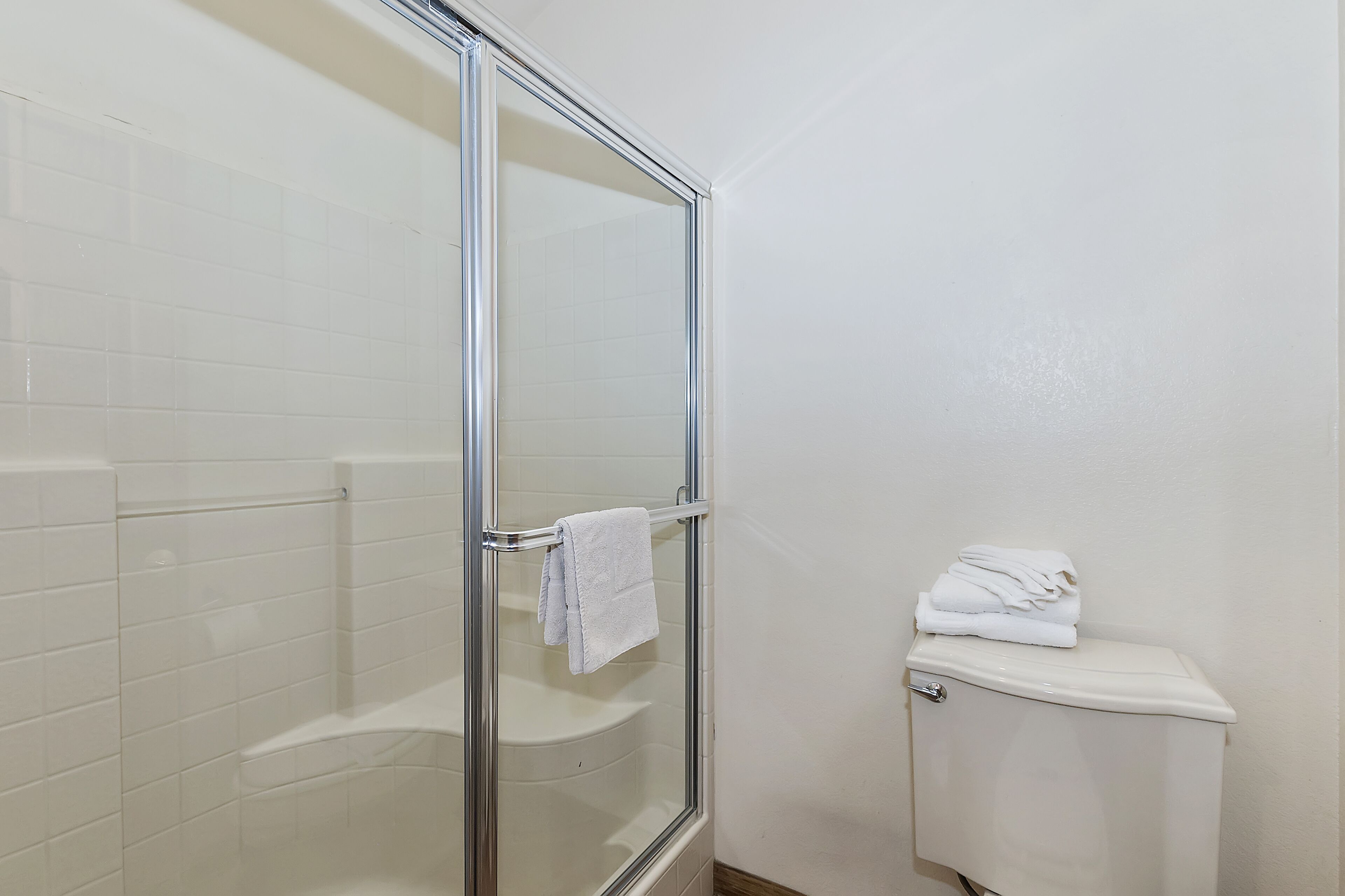 Um banheiro com box de vidro, vaso sanitário branco e porta-toalhas com toalhas dobradas.