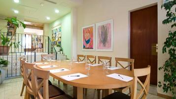 Uma sala de jantar com uma mesa redonda posta para seis pessoas, rodeada por cadeiras de madeira com assentos acolchoados.