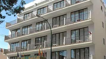 Um hotel com vários andares, varandas, uma loja no nível da rua e o letreiro 'yela' visível.
