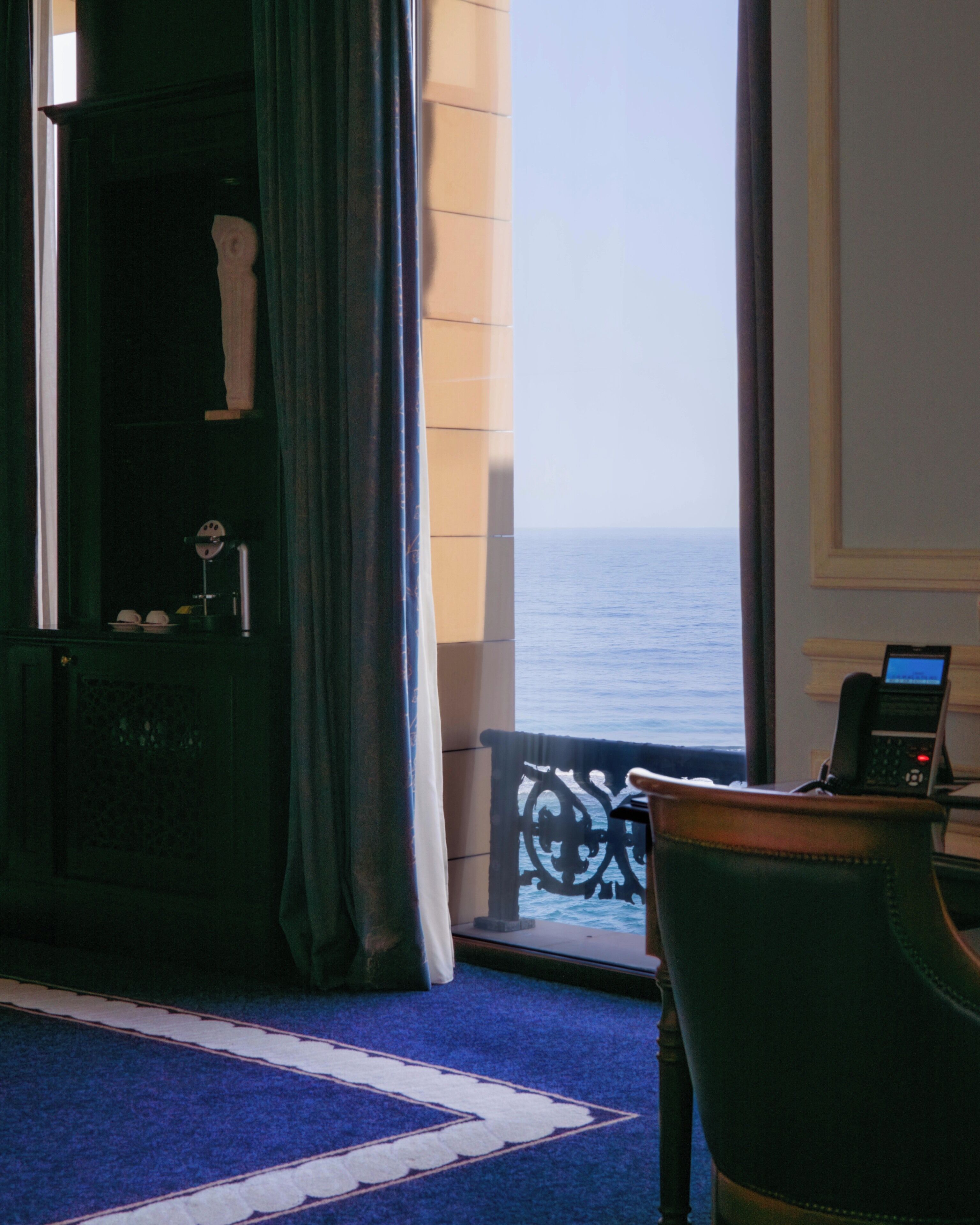 Quarto com vista para o mar, uma mesa com telefone e uma cadeira.