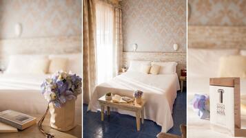 Quarto de hotel com uma cama, uma mesa de cabeceira com um livro e um vaso de flores, e um aviso do Ostiá Antica Park Hotel.