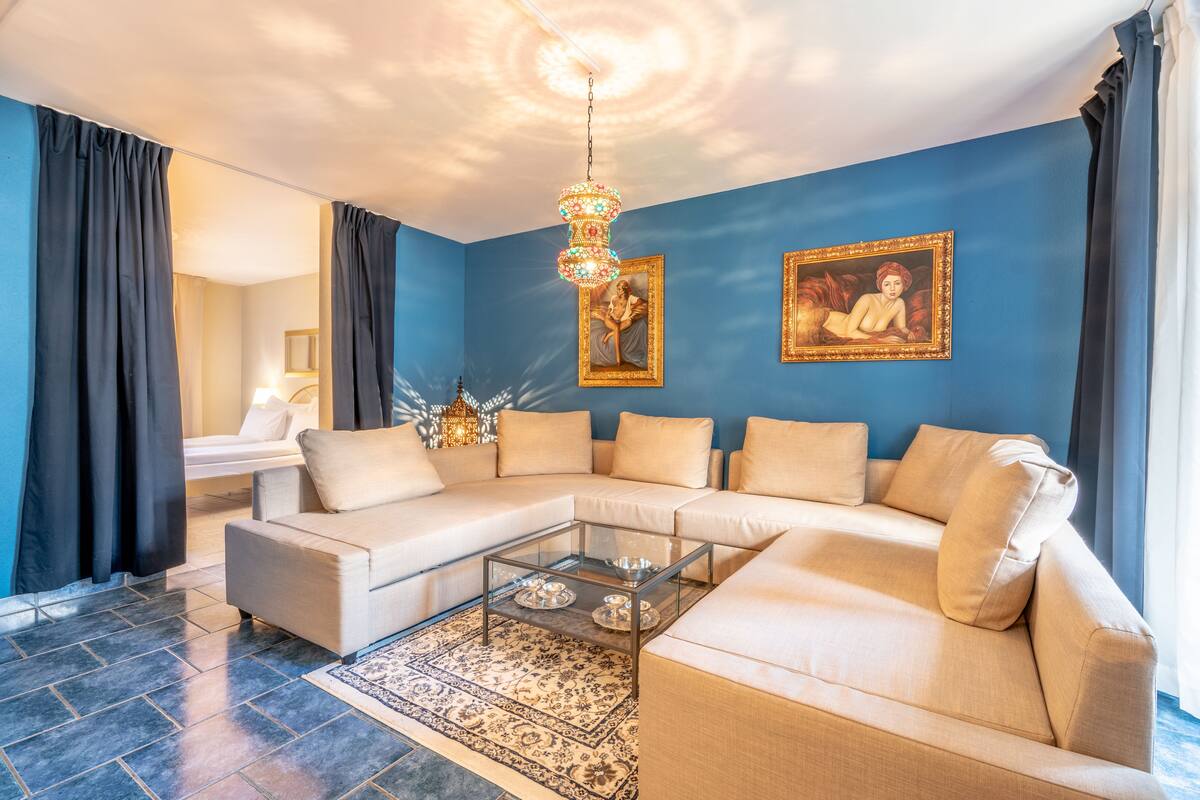 Uma sala de estar moderna com um sofá seccional, uma mesa de centro de vidro e um candelabro.