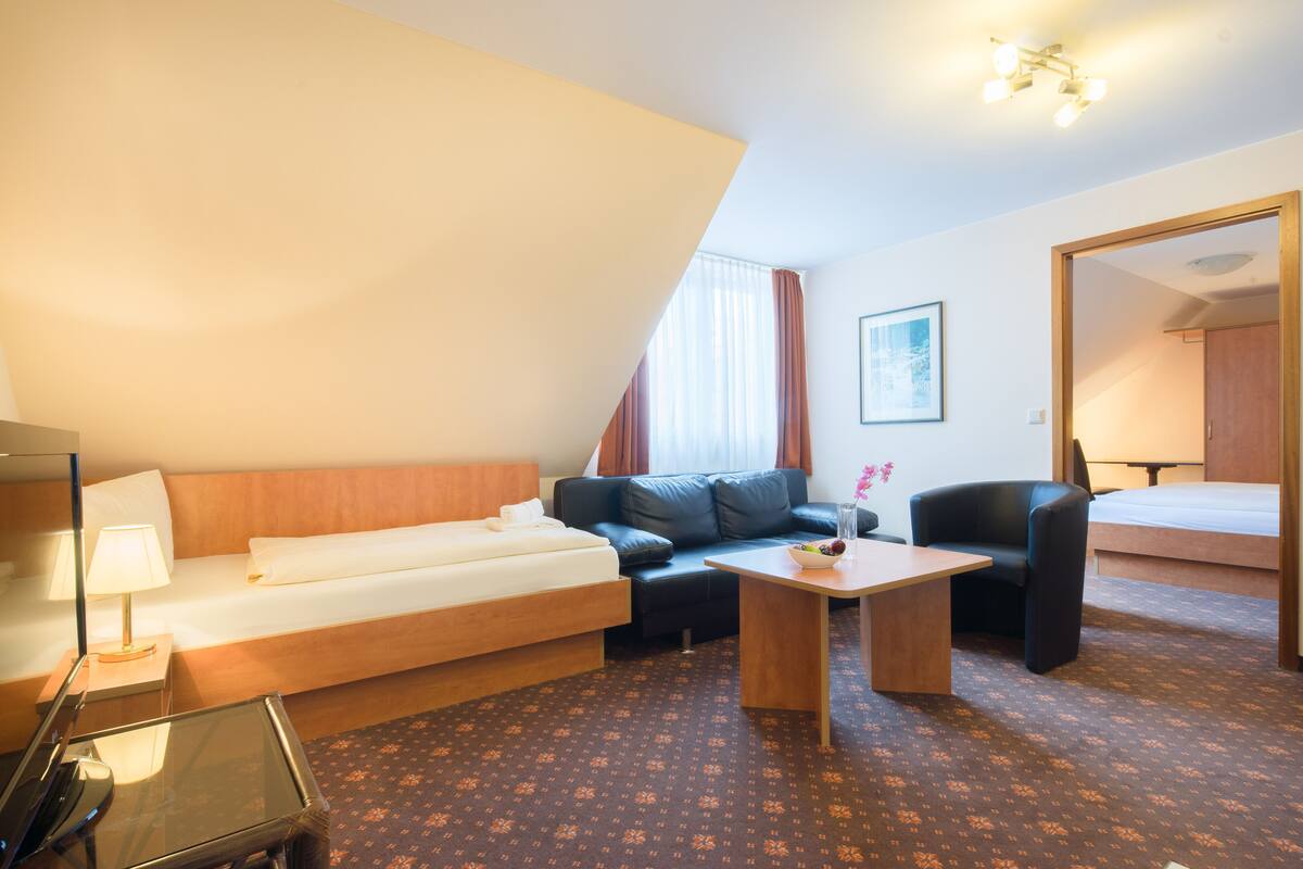 Quarto de hotel com cama, sofá, escrivaninha e cadeira.