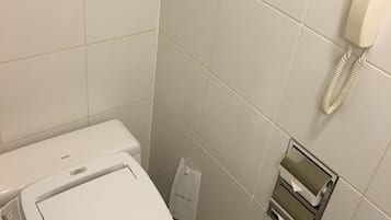 Uma casa de banho moderna com sanita, secador de mãos e dispensador de papel.