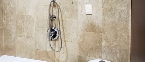 Um banheiro com banheira, vaso sanitário e porta-toalhas com toalhas dobradas.