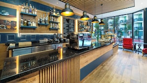 Uma área de bar com prateleiras de madeira, uma máquina de café e uma cadeira vermelha.
