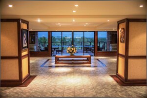 Um hall com balcão de recepção, um banco e uma janela ampla com vista para o exterior.