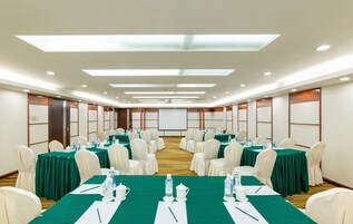Uma sala de conferência com mesas, cadeiras e um projetor.
