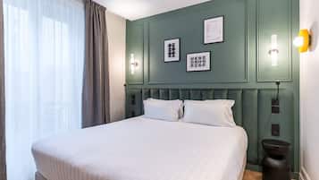Quarto de hotel com cama, janela com cortinas e luminárias fixadas na parede.