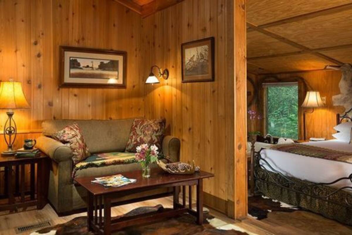 Um quarto aconchegante com paredes de madeira, um sofá, uma cama e uma mesa com abajur.